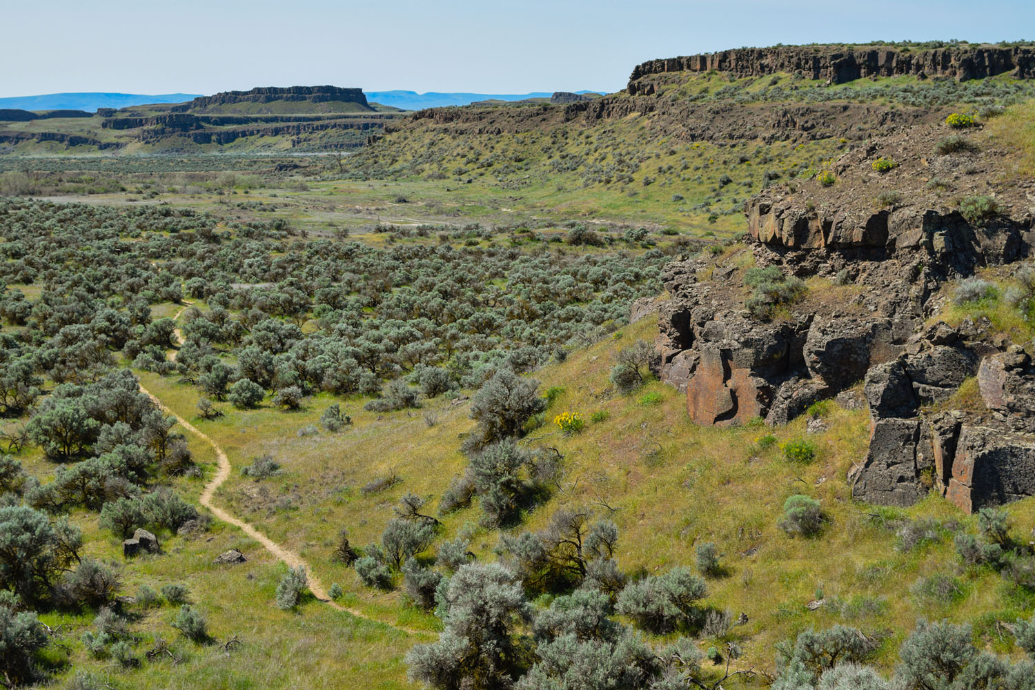 A trail winds down through sagebrush into a valley below during ...