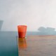 A photo of a red-orange cup on a wooden table, with shadows behind