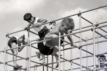 A black-and-white image of children playing on a jungle gym.