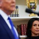 Tulsi Gabbard looks to the side at Donald Trump