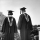 Two graduates walking in caps and gowns