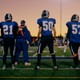 a blurry color photograph of a high-school football team on the field at night