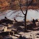 photo of people sitting on rocks next to water with fall foliage