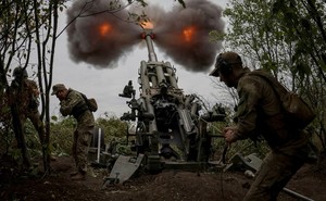 Three soldiers operate a piece of field artillery, firing a shell and ...
